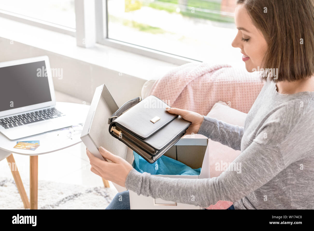 Young woman opening parcel with new purchase at home Stock Photo - Alamy