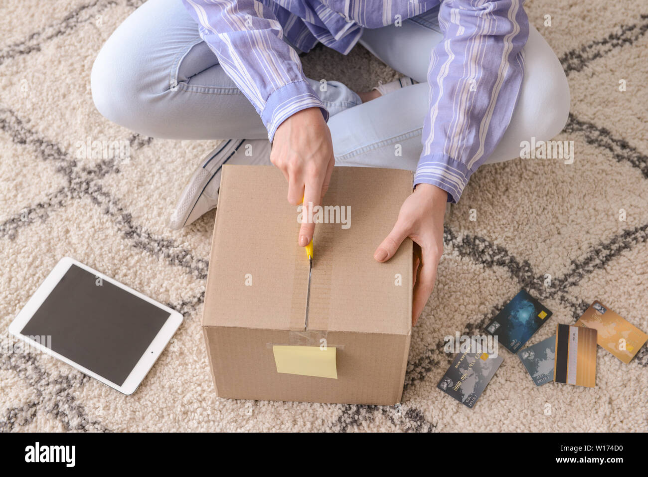 Young woman opening parcel at home Stock Photo - Alamy