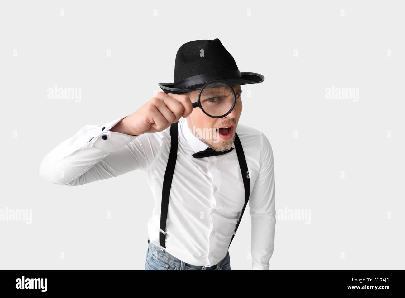 Male detective with magnifying glass on light background Stock Photo ...