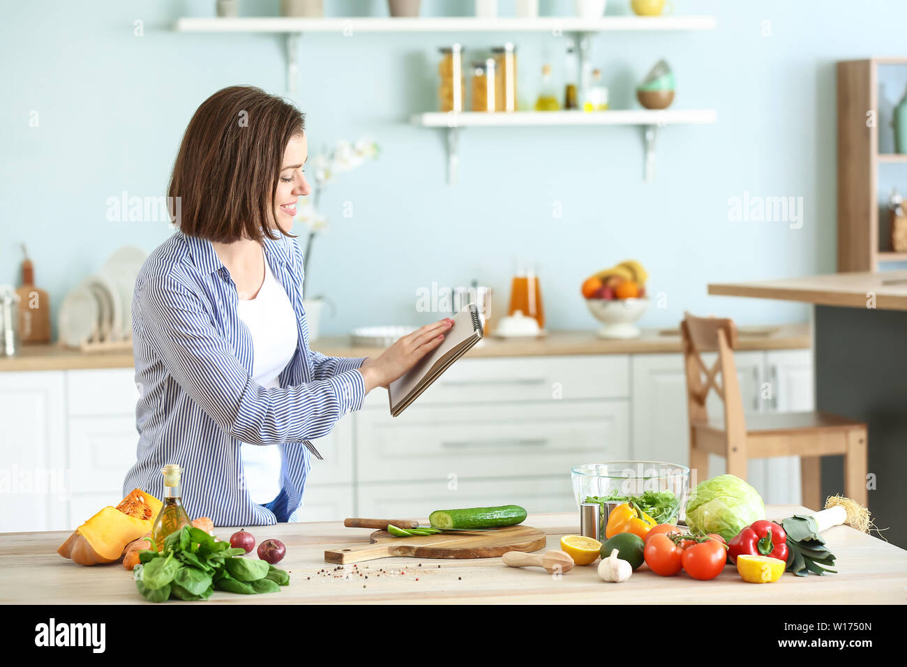 Young woman with recipe book cooking in kitchen Stock Photo - Alamy