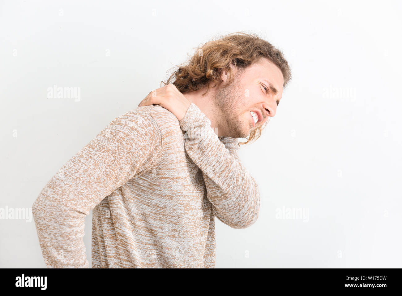 Young man suffering from pain in shoulder on white background Stock ...