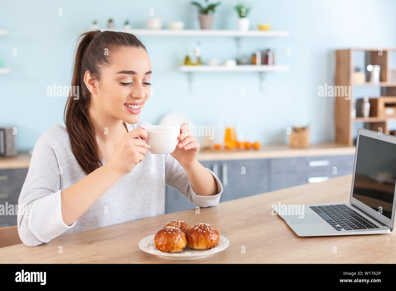 Beautiful woman eating at table in kitchen Stock Photo - Alamy