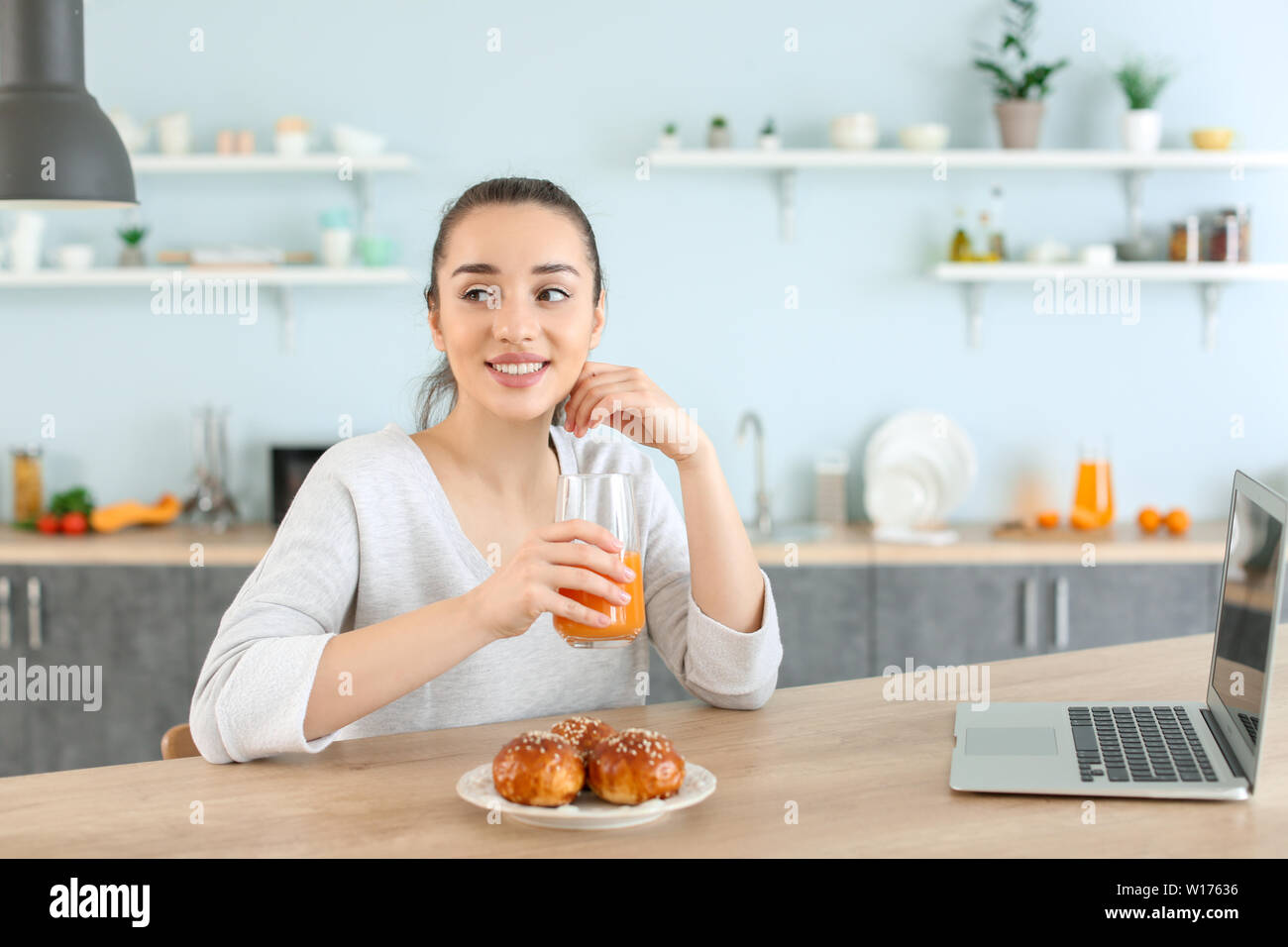 Beautiful woman eating at table in kitchen Stock Photo - Alamy