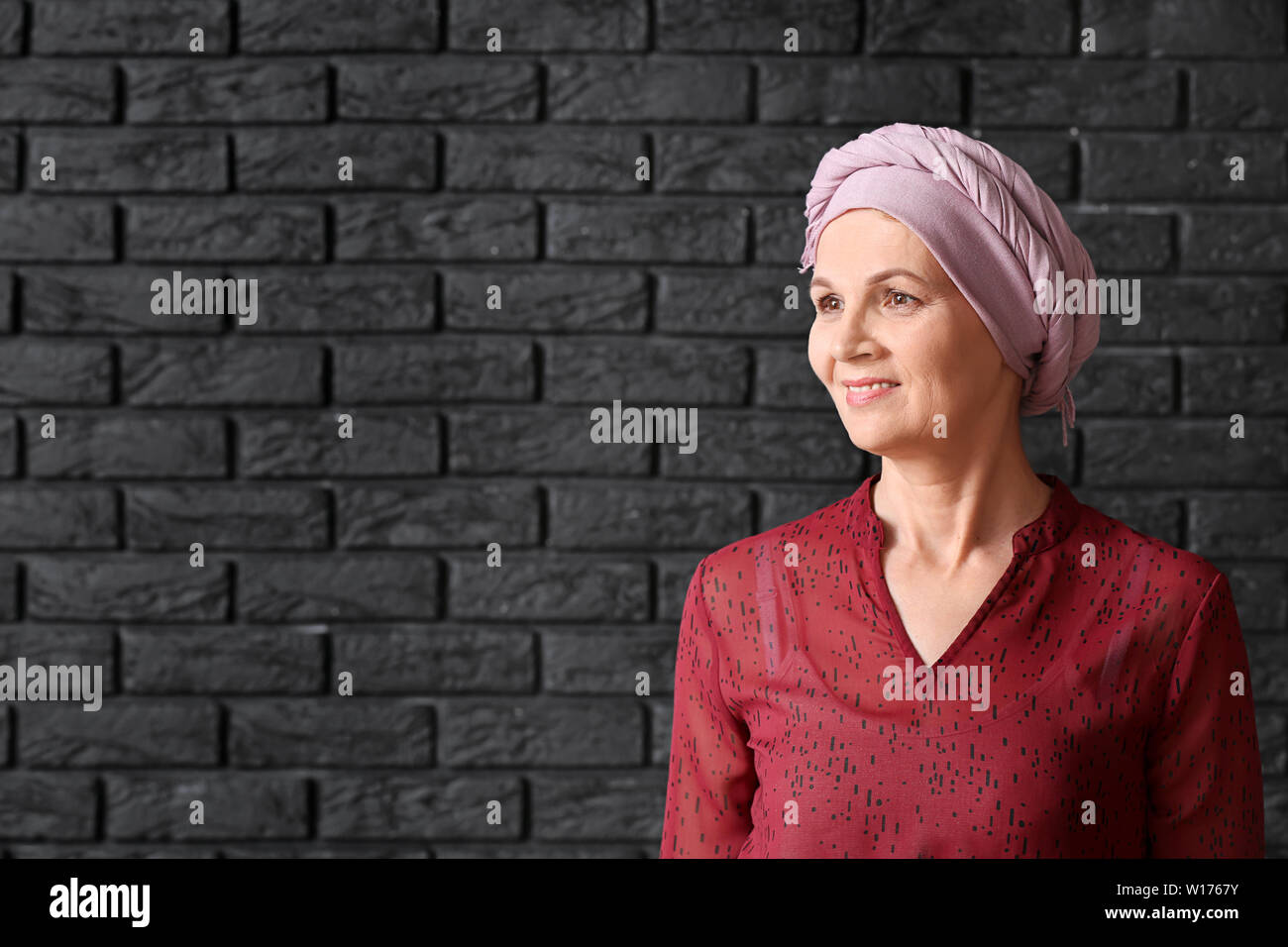 Mature woman after chemotherapy on dark brick background Stock Photo ...