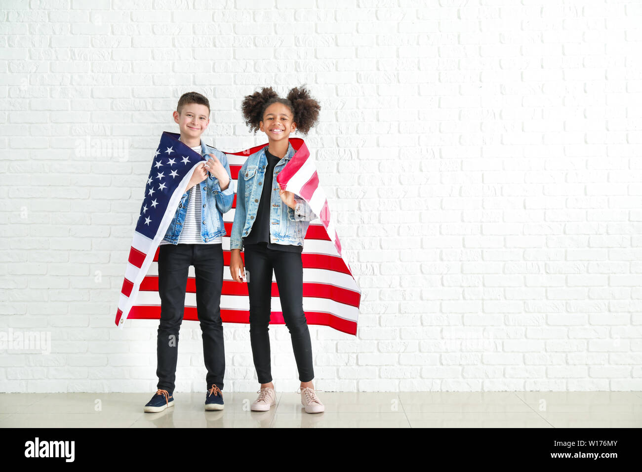 Cute children with national flag of USA near white brick wall Stock ...