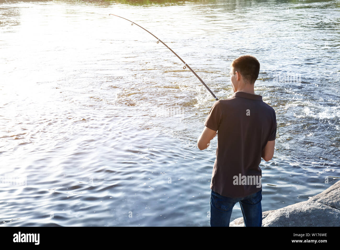 Young man fishing in river Stock Photo - Alamy