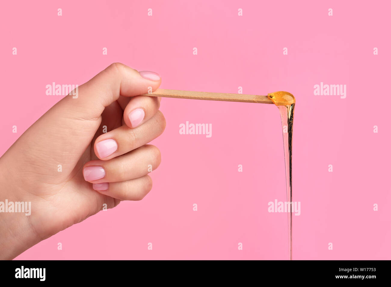 Female hand with sugaring paste on stick against color background Stock ...