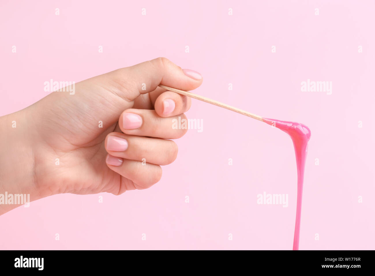 Female hand with sugaring paste on stick against color background Stock ...