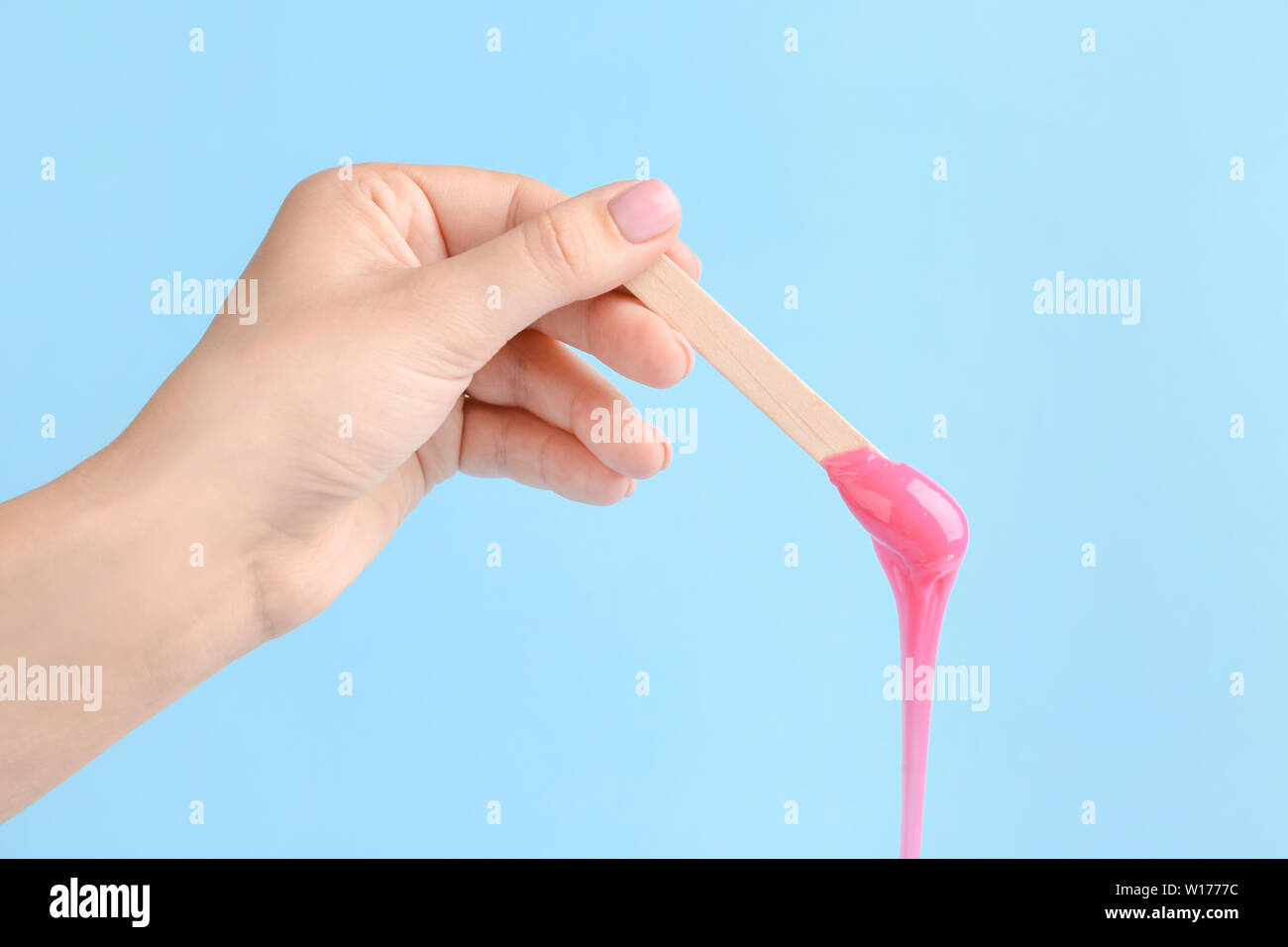 Female hand with sugaring paste on stick against color background Stock ...
