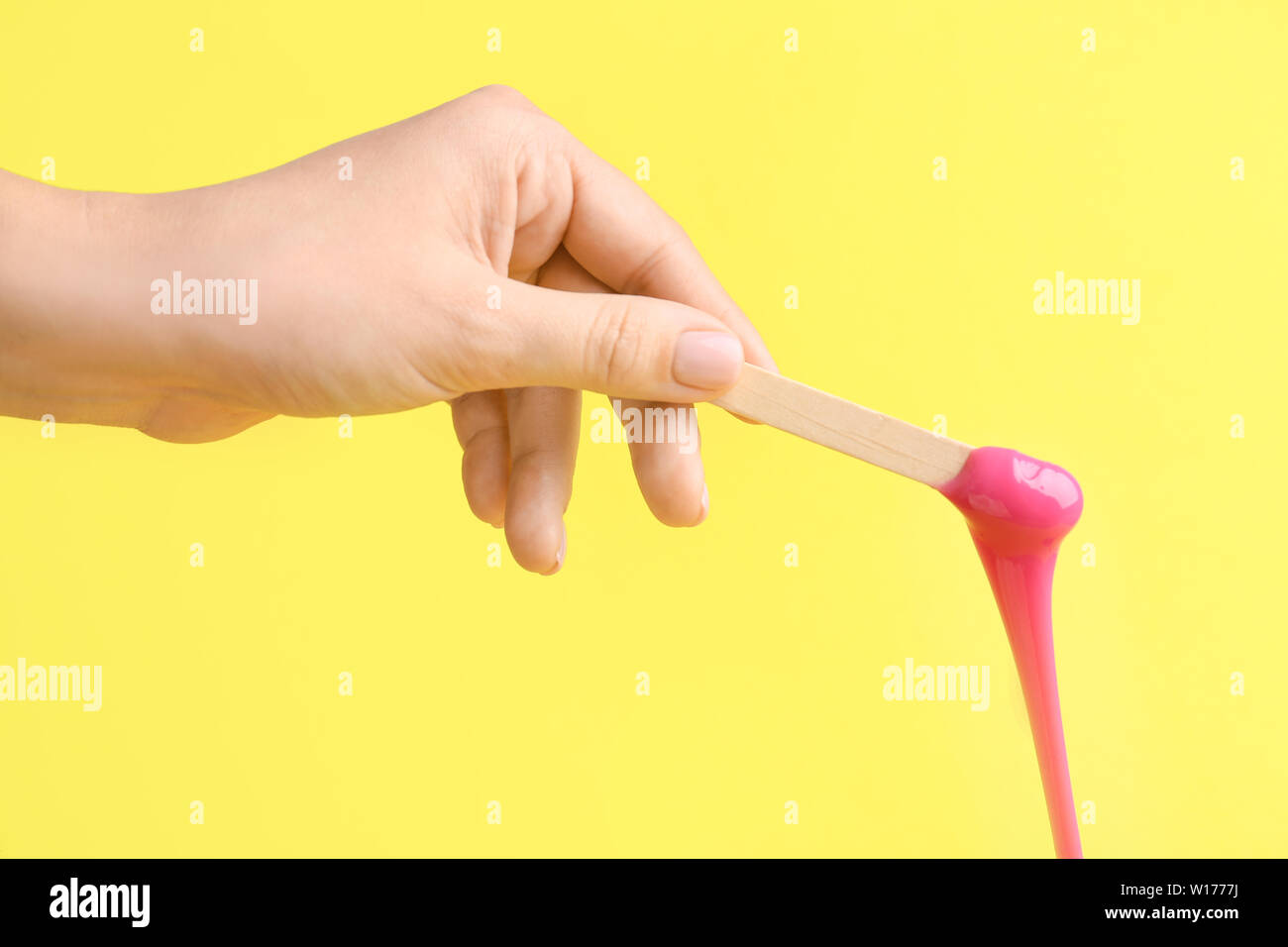 Female hand with sugaring paste on stick against color background Stock ...