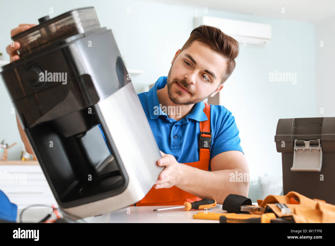 Man repairing coffee machine in kitchen Stock Photo - Alamy