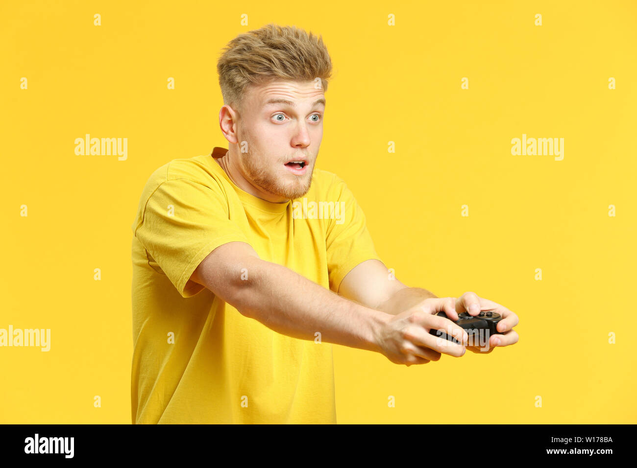 Portrait of stressed young man playing video games on color background ...