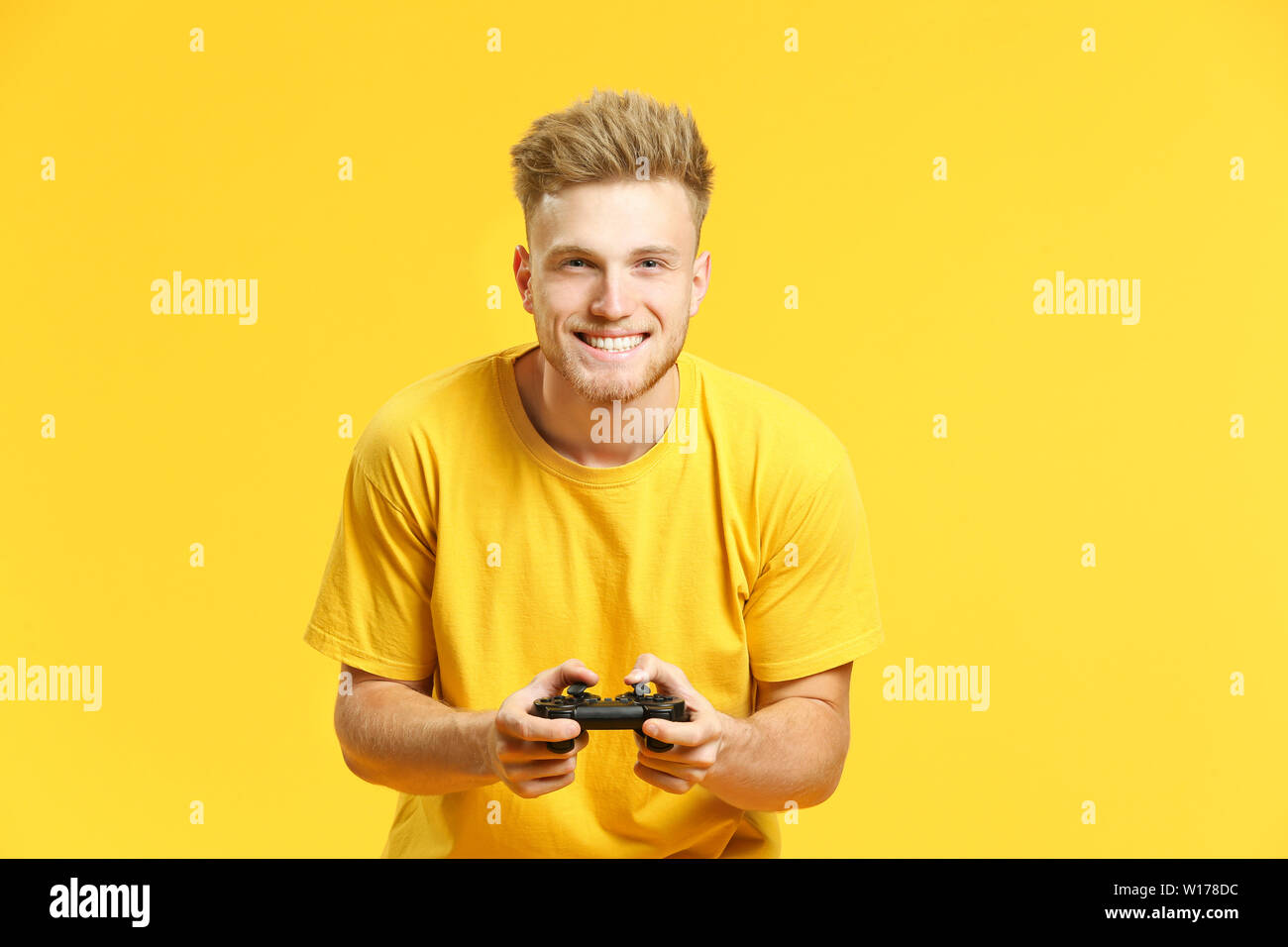 Portrait of handsome young man playing video games on color background ...