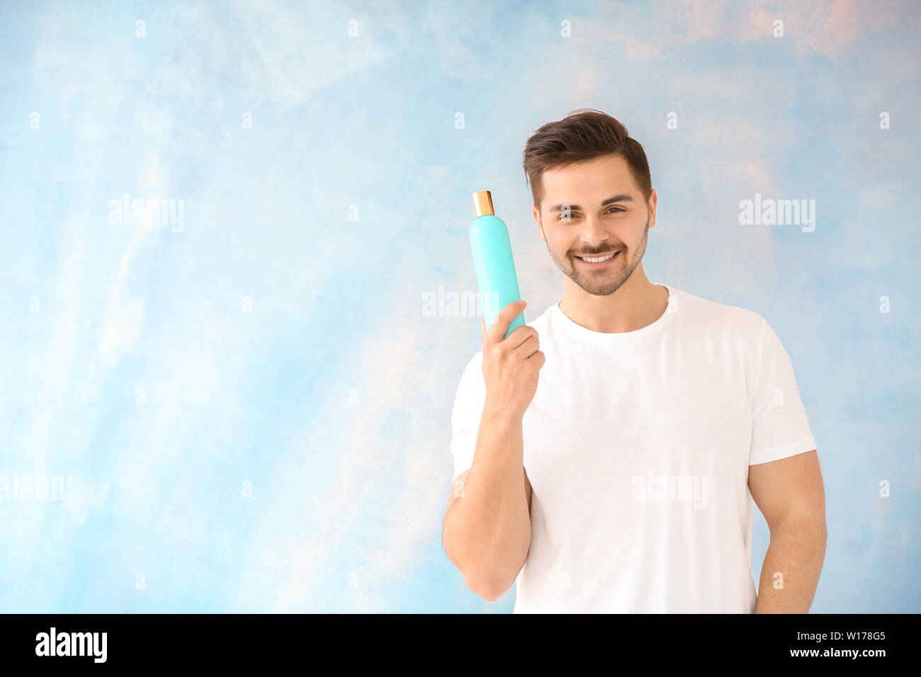 Handsome man with bottle of shampoo on light background Stock Photo - Alamy