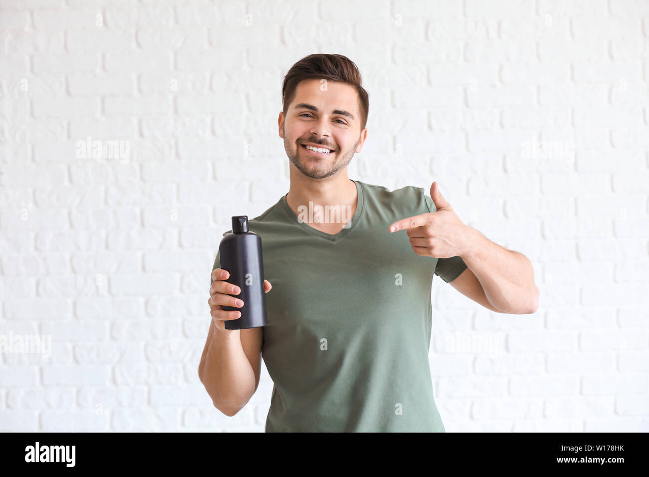 Handsome man with bottle of shampoo on white background Stock Photo - Alamy