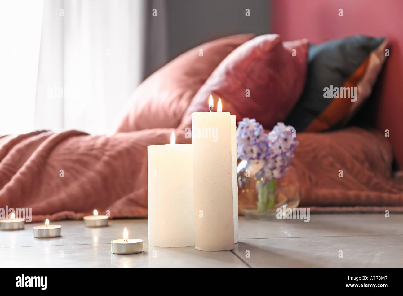 Beautiful burning candles on floor in room Stock Photo - Alamy