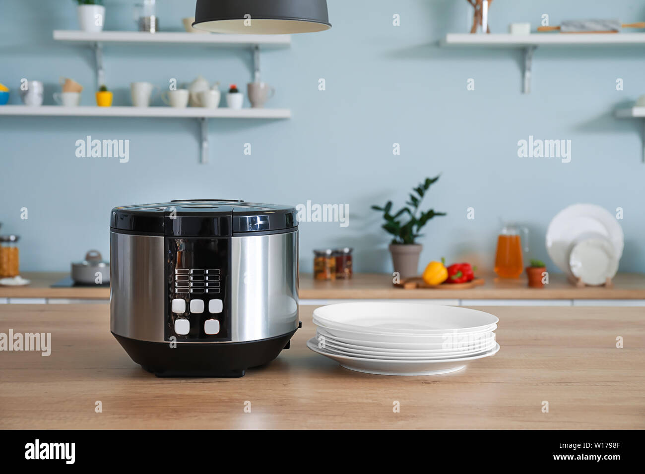 Modern multi cooker and plates on table in kitchen Stock Photo - Alamy
