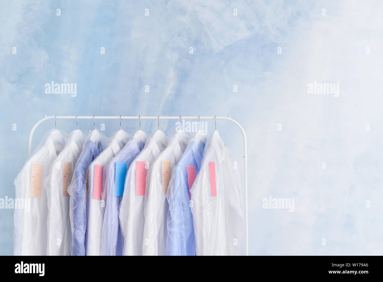 Rack with clothes after dry-cleaning on light background Stock Photo ...