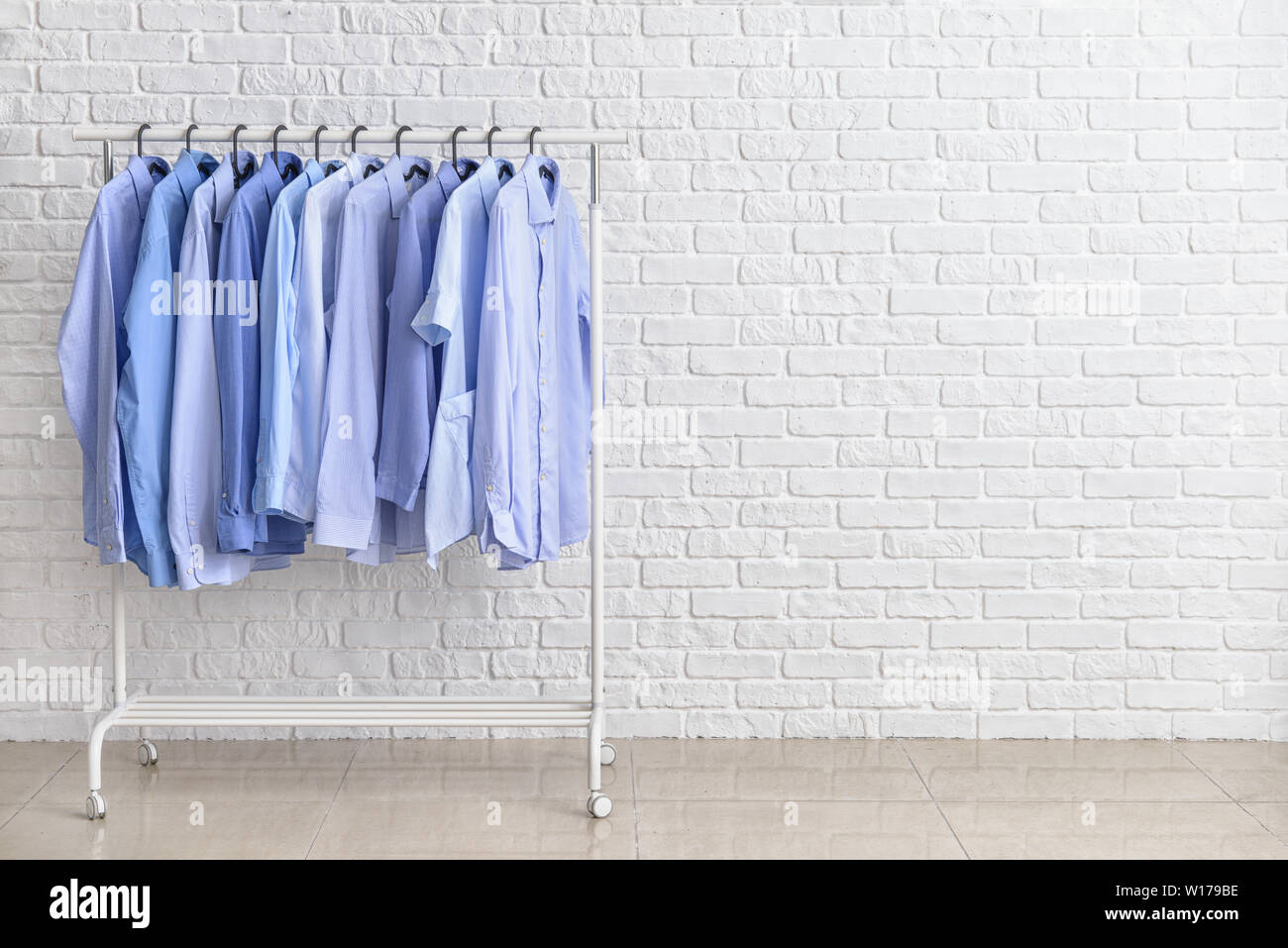 Rack with clothes after dry-cleaning near white brick wall Stock Photo ...