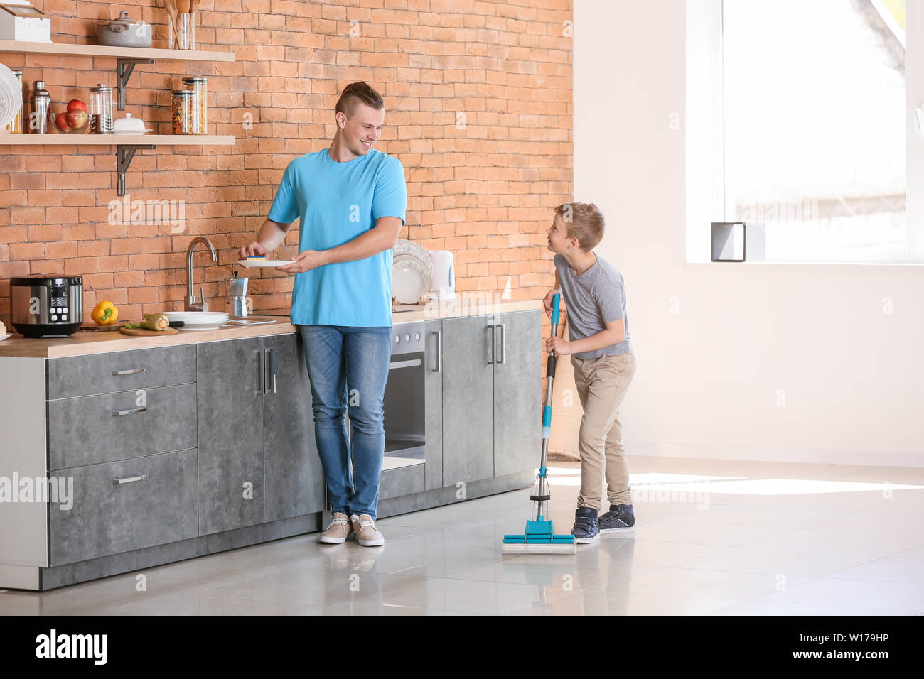 Father and son cleaning kitchen together Stock Photo - Alamy