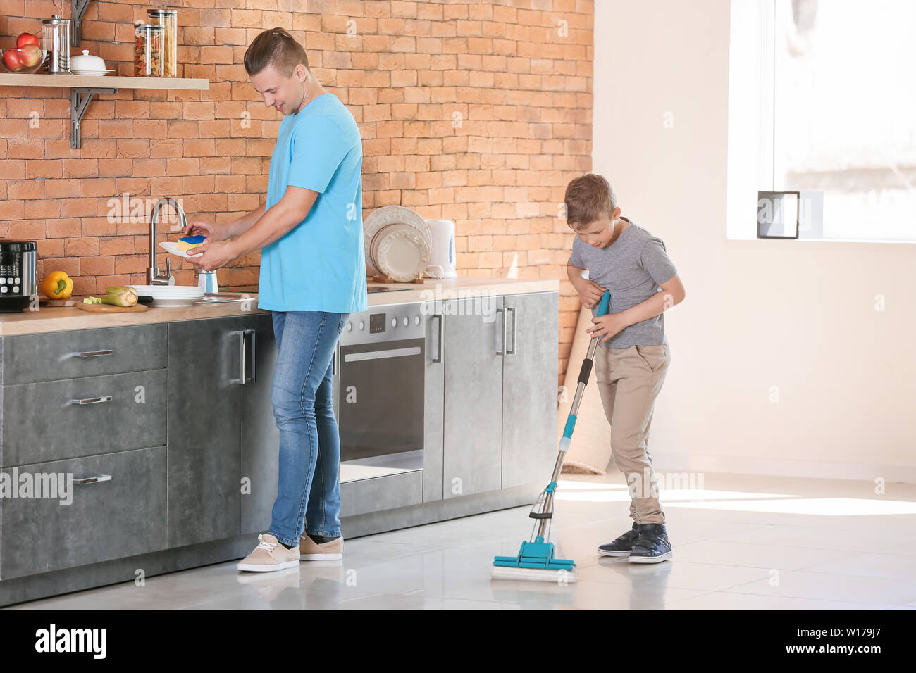 Father and son cleaning kitchen together Stock Photo - Alamy