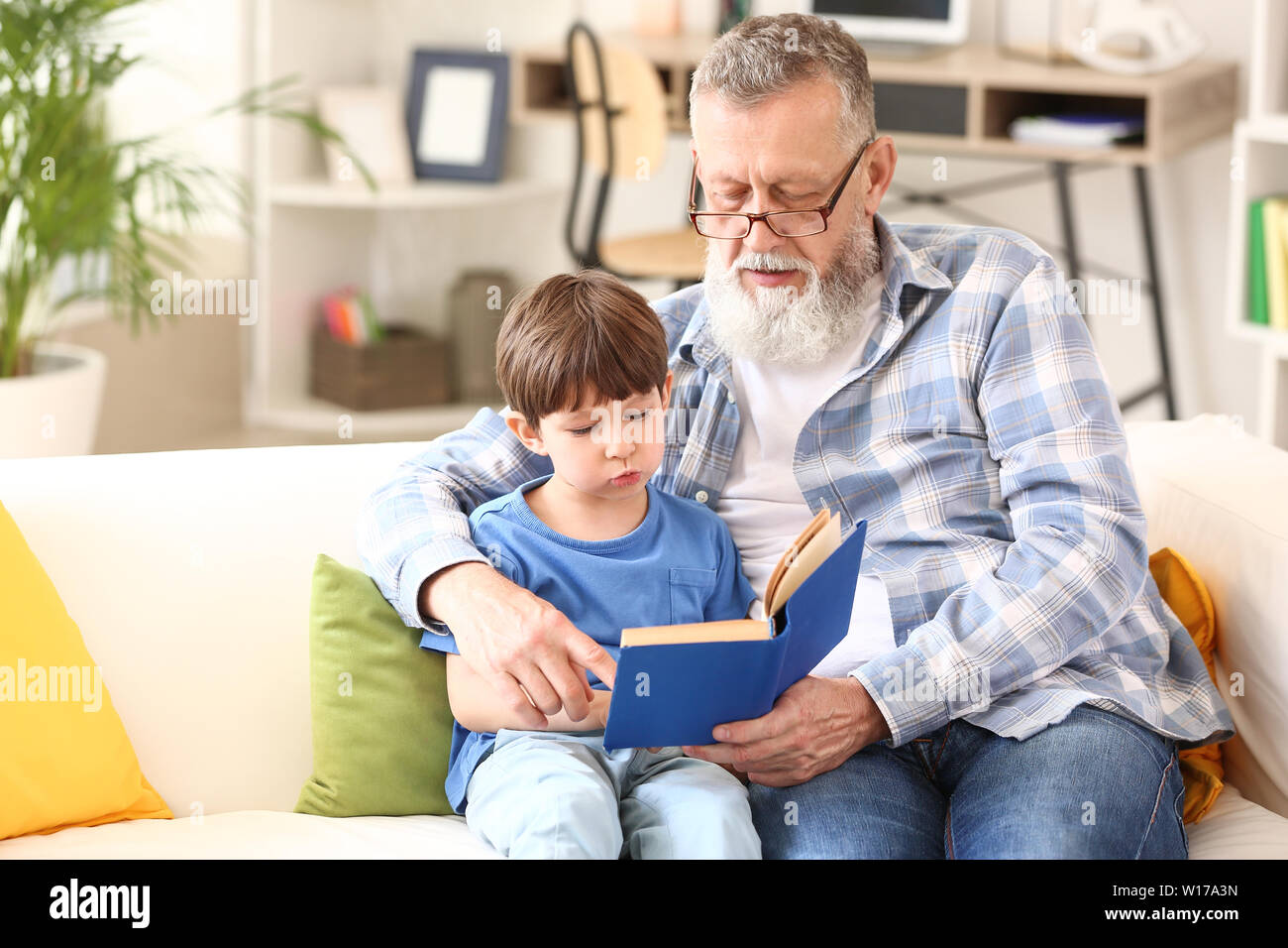 Cute little boy reading book with grandfather at home Stock Photo - Alamy