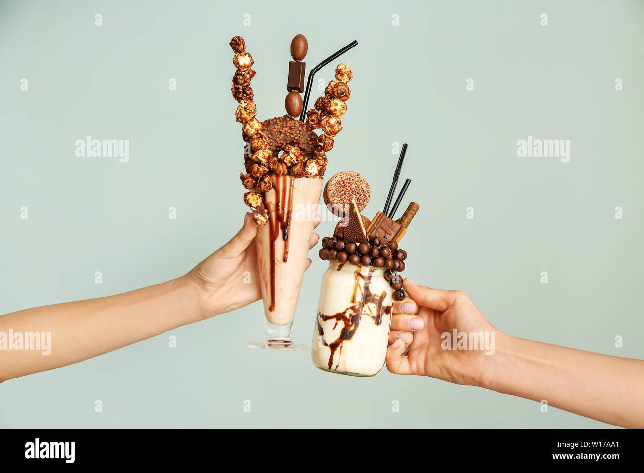 Female hands with delicious freak shakes on grey background Stock Photo ...