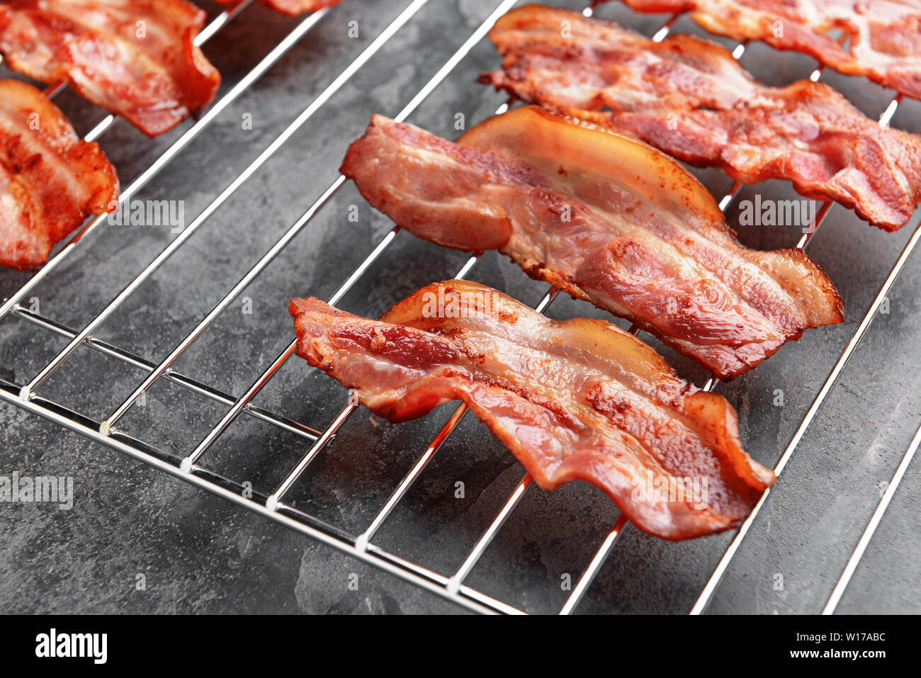 Cooling rack with tasty fried bacon on grey background Stock Photo - Alamy