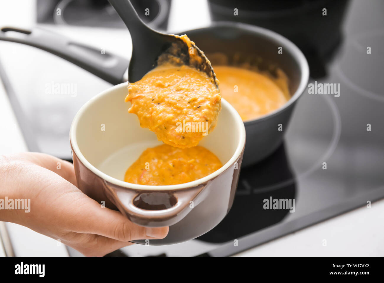 Woman pouring delicious cream soup into pot, closeup Stock Photo - Alamy