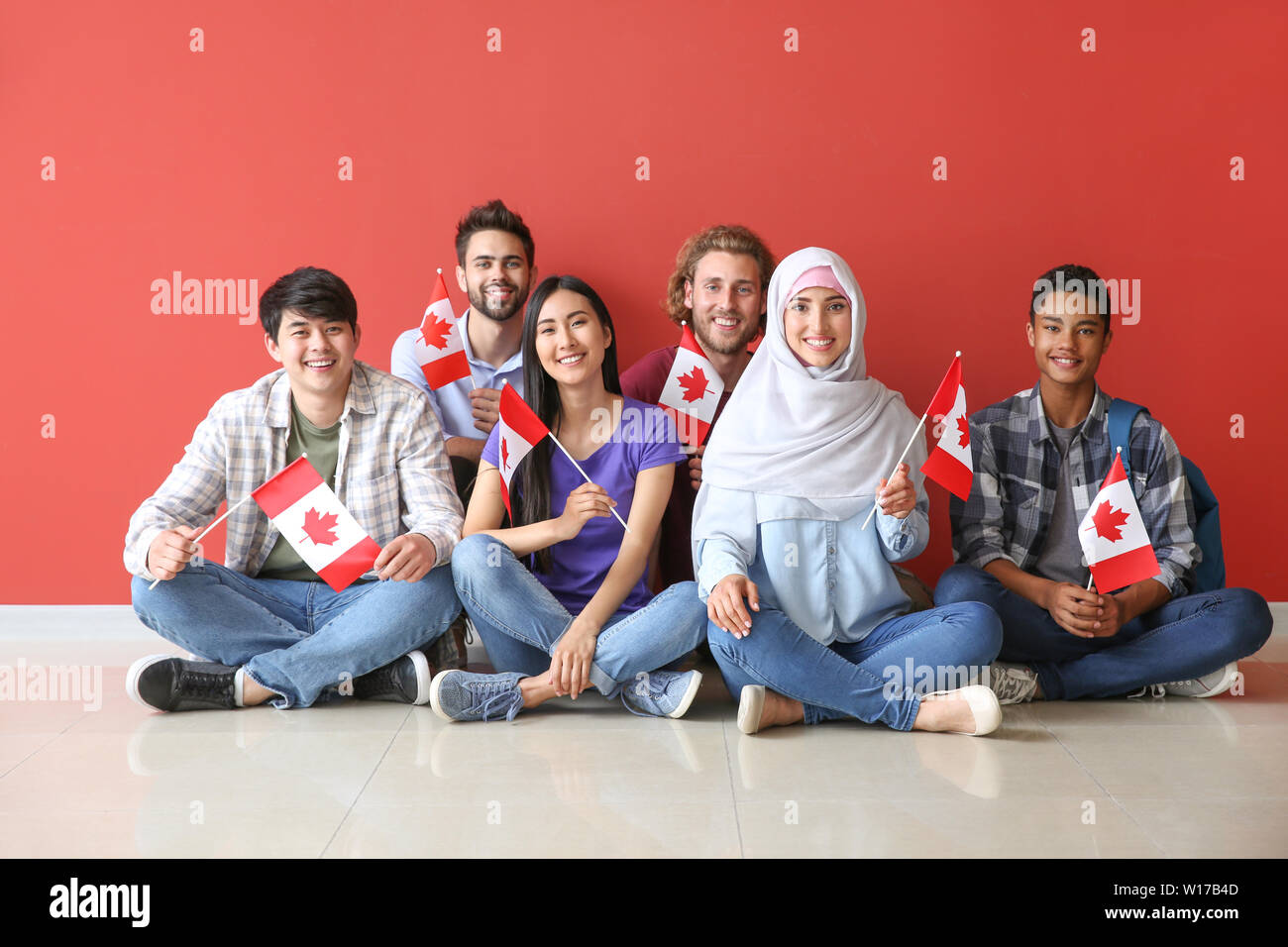 Group of students with Canadian flags sitting near color wall Stock ...