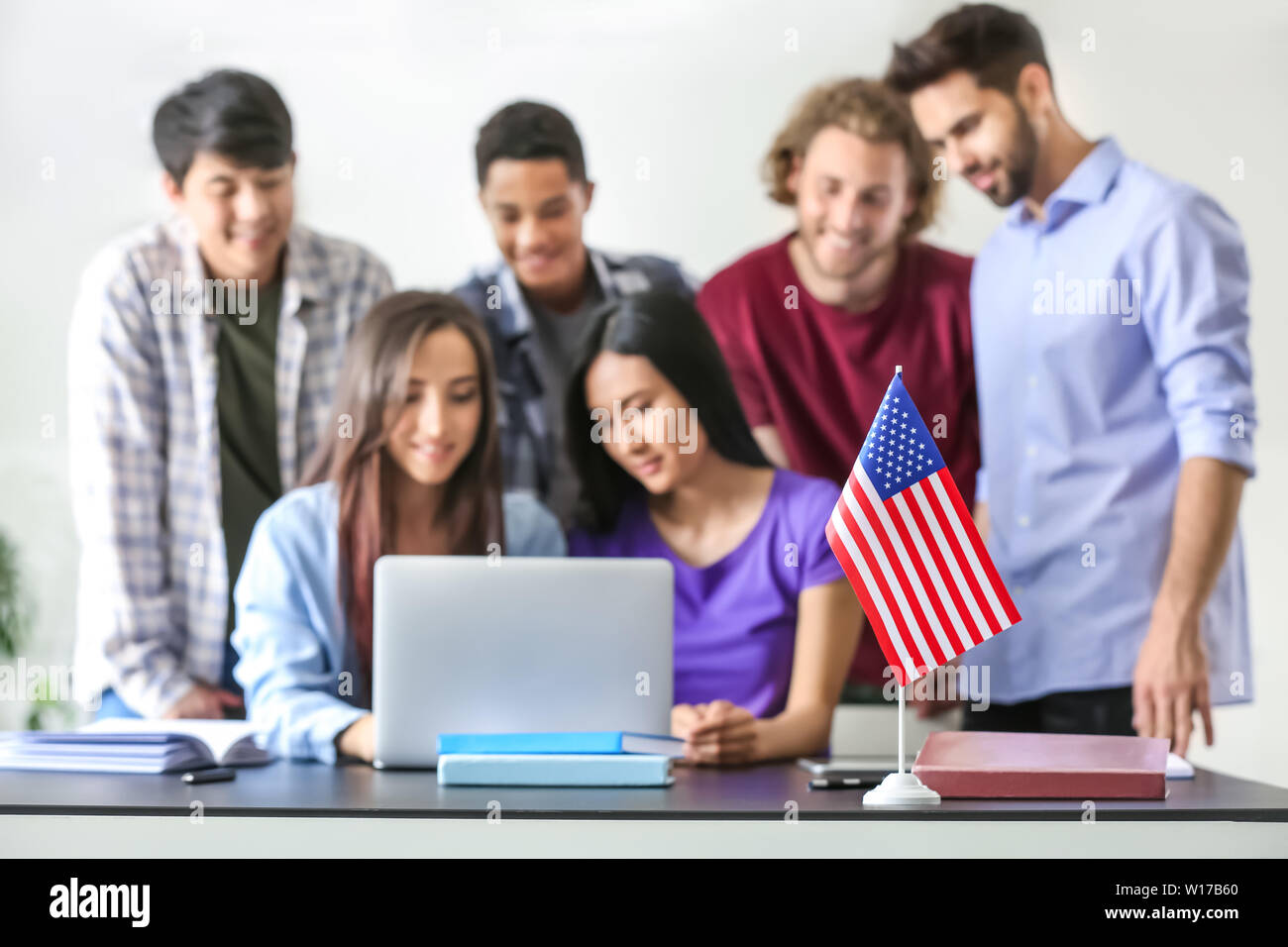 Group of students at table with laptop in classroom Stock Photo - Alamy