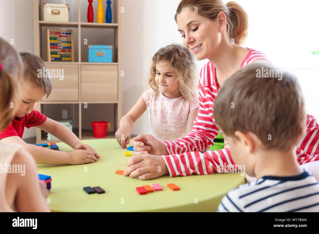 Nursery teacher with cute little children in kindergarten Stock Photo ...