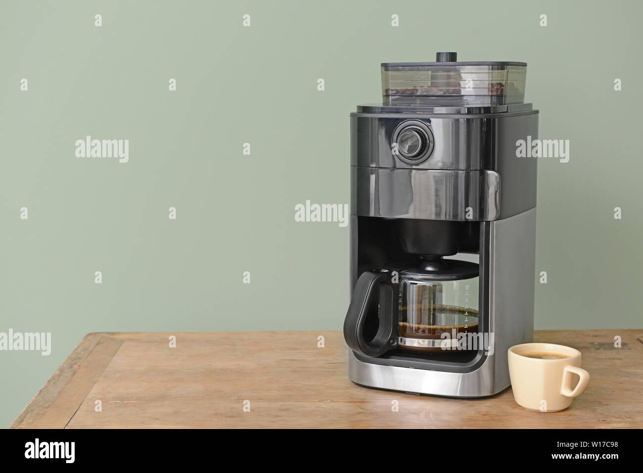 Modern coffee machine and cup on table against color background Stock ...