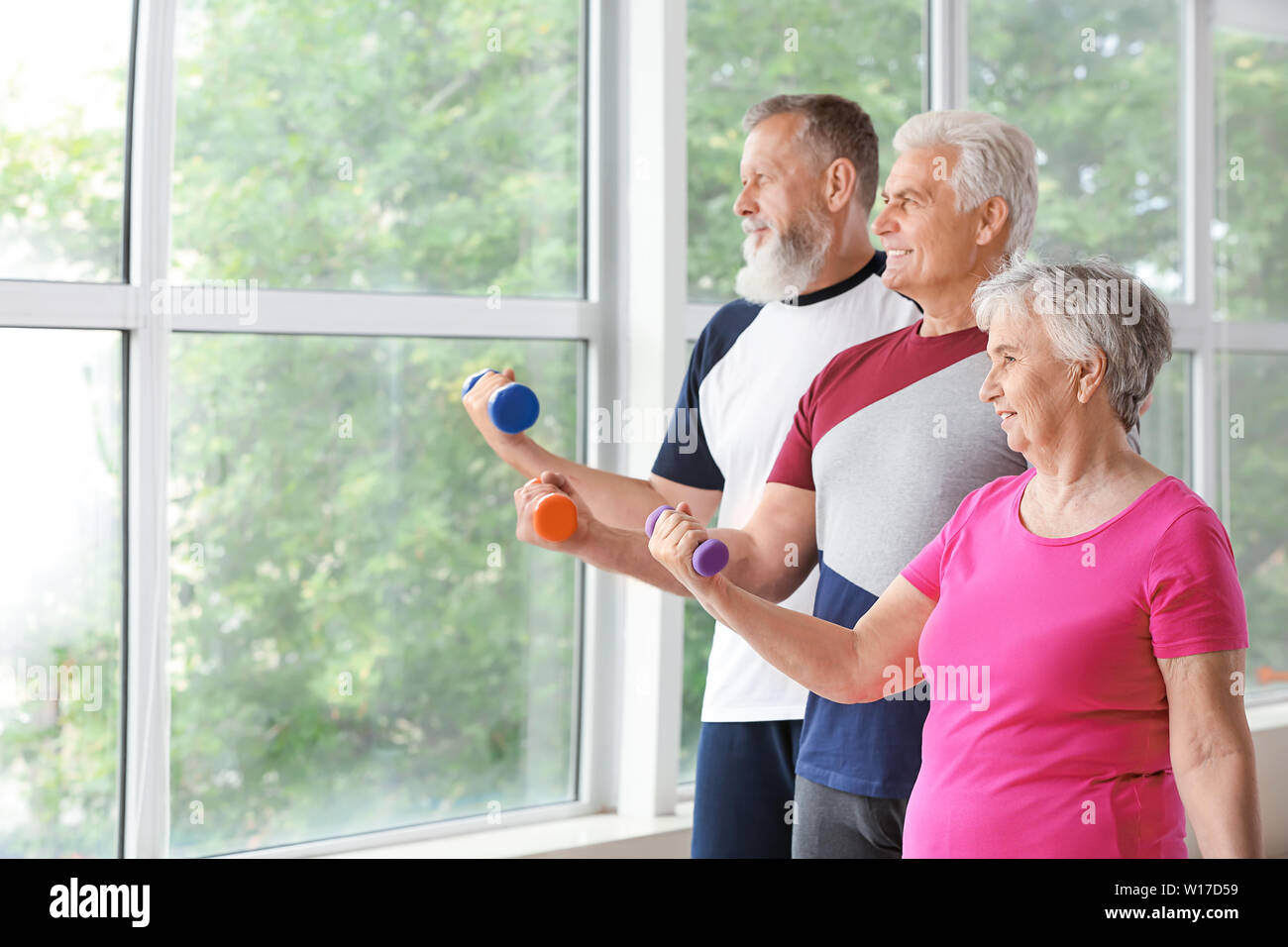 Elderly people training with dumbbells in gym Stock Photo - Alamy