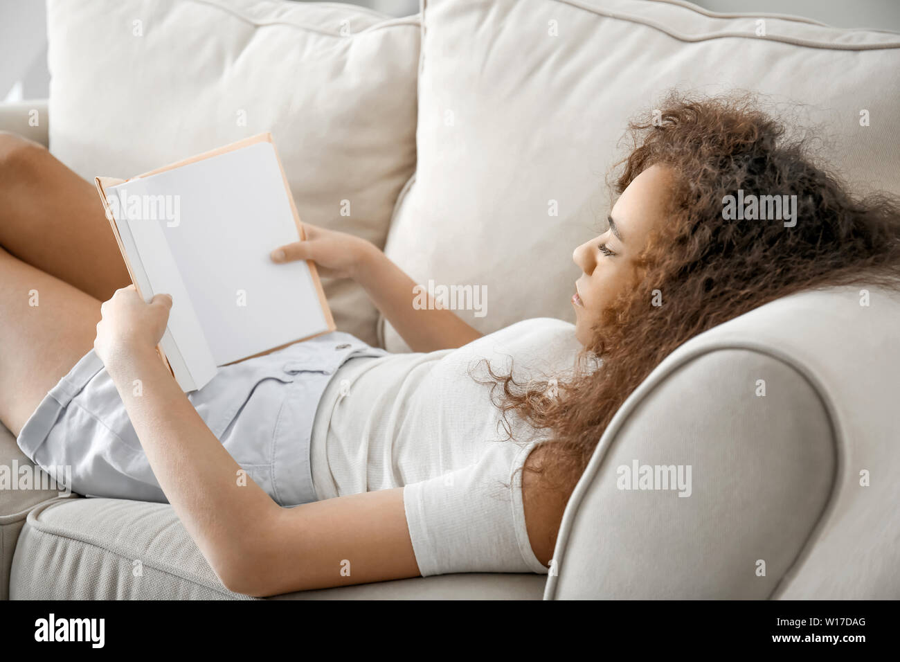 Beautiful young woman reading book at home Stock Photo - Alamy