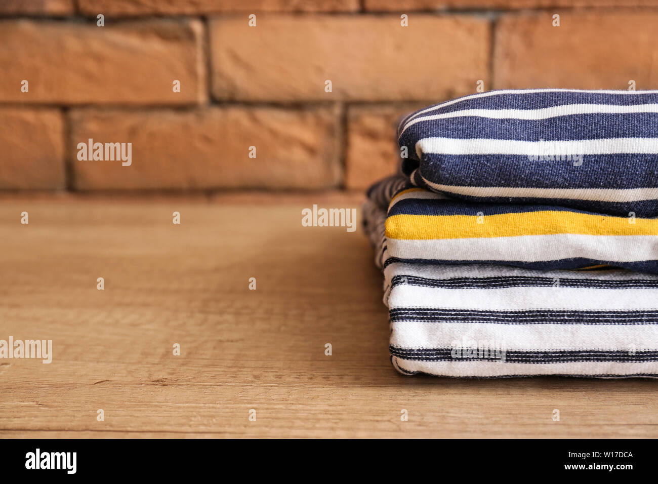 Stack of clothes on table against brick wall Stock Photo - Alamy