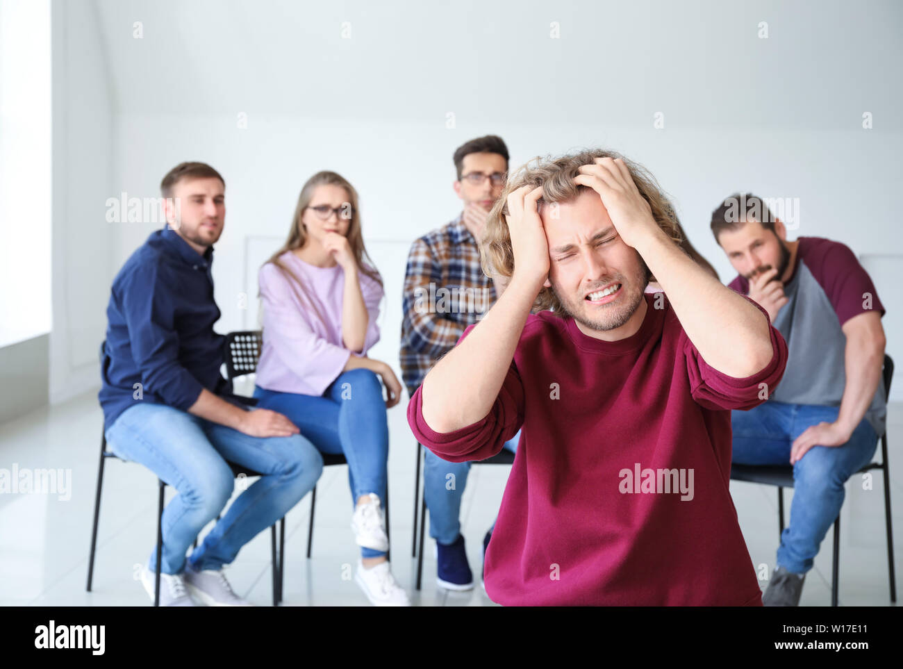 Stressed young man at group therapy session Stock Photo - Alamy