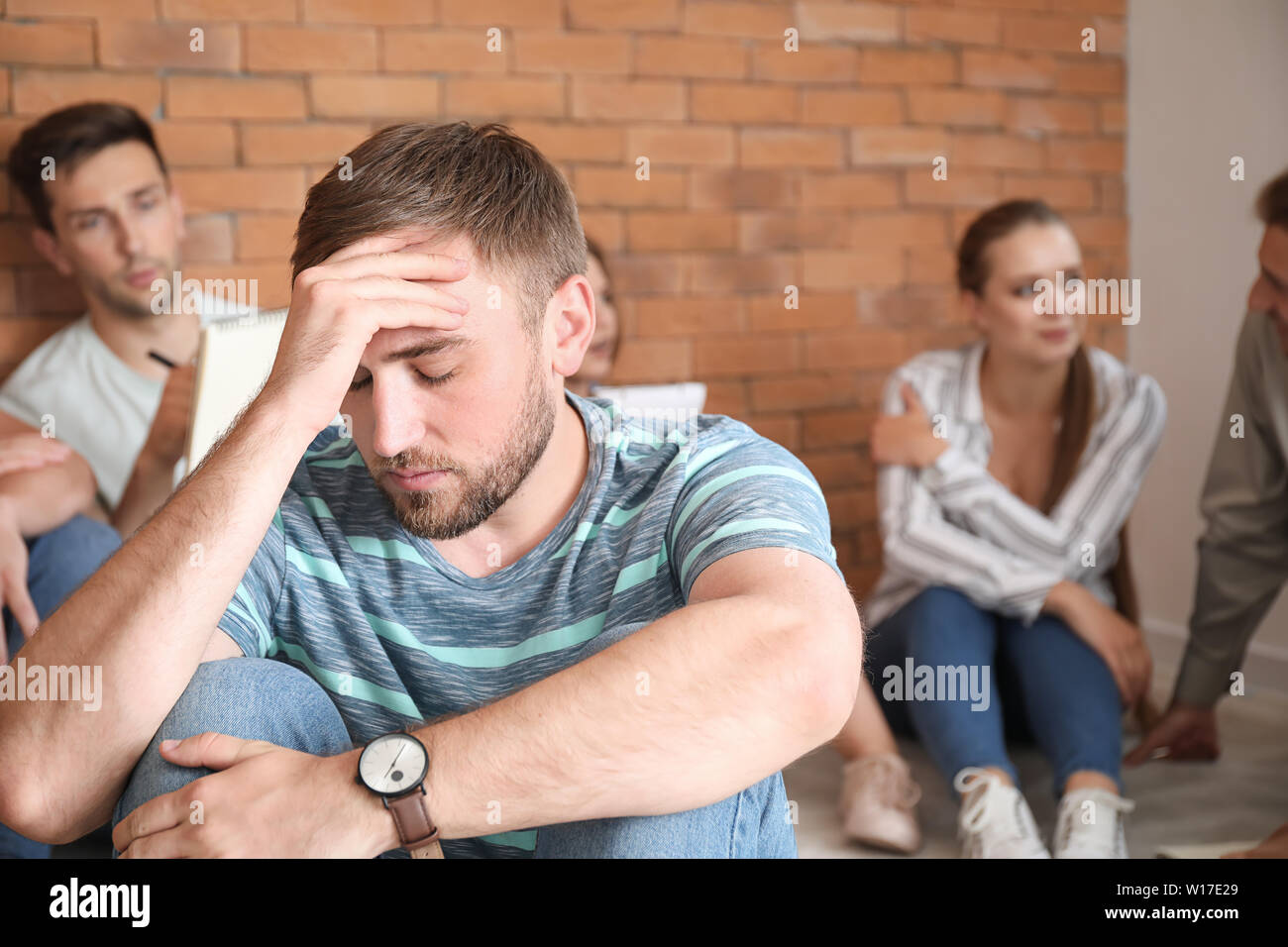 Sad young man at group therapy session Stock Photo - Alamy