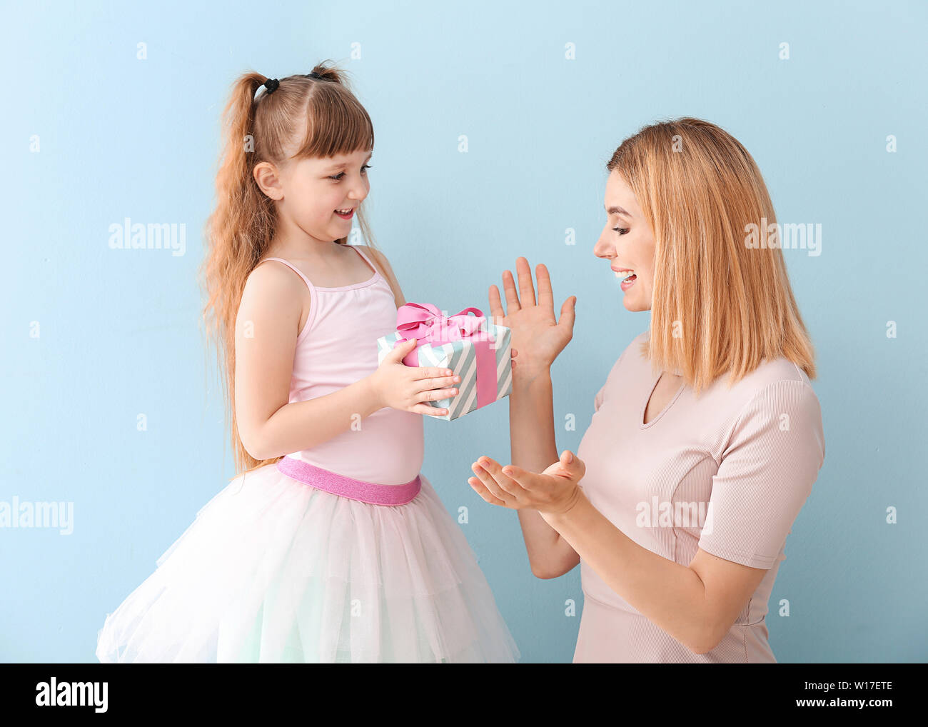 Little girl greeting her mother on color background Stock Photo - Alamy