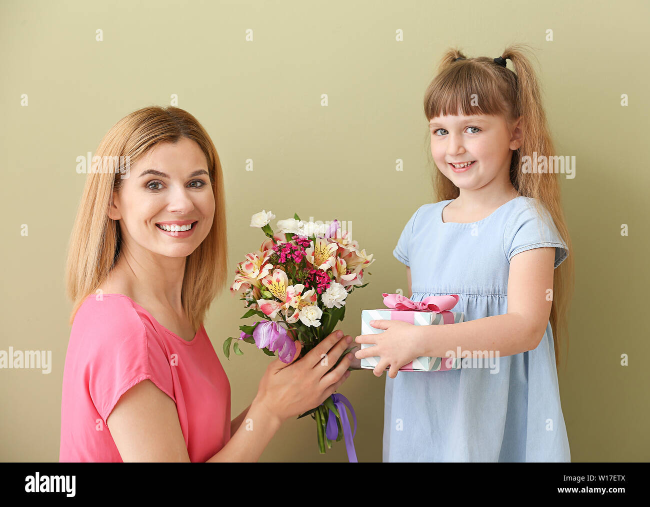 Little girl greeting her mother on color background Stock Photo - Alamy