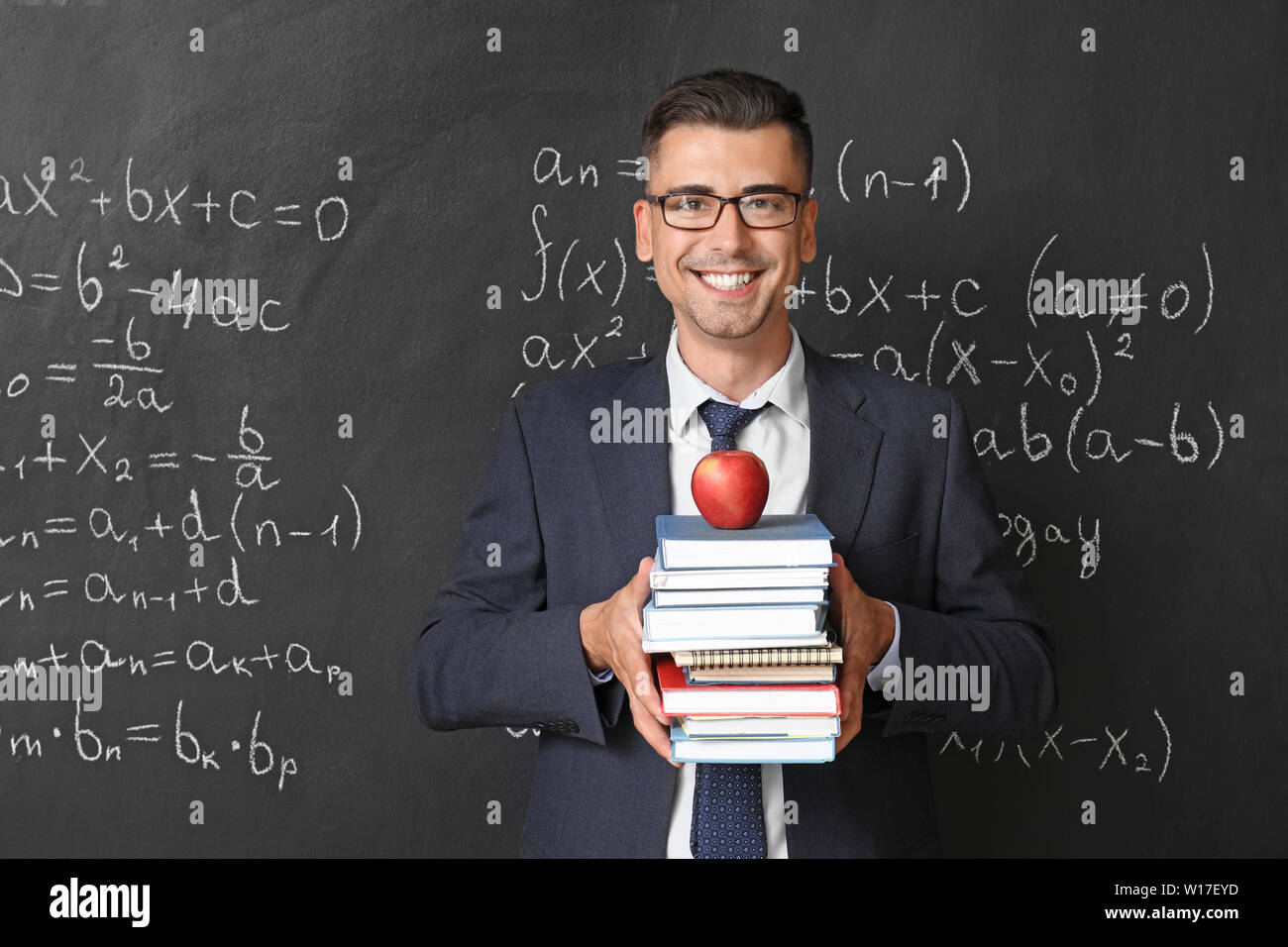 Handsome math teacher with books near blackboard in classroom Stock ...