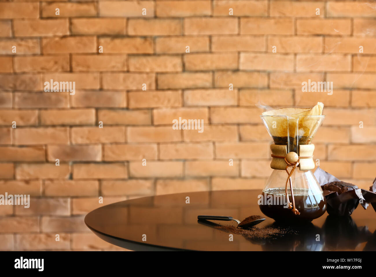 Chemex with hot coffee on table against brick background Stock Photo ...