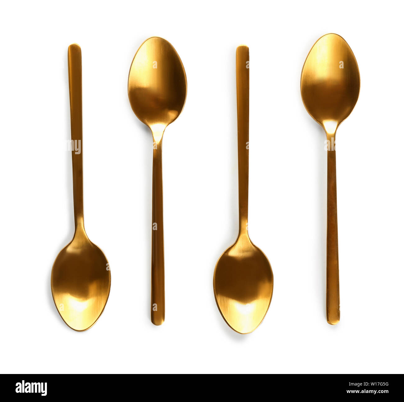 Golden spoons on white background Stock Photo - Alamy