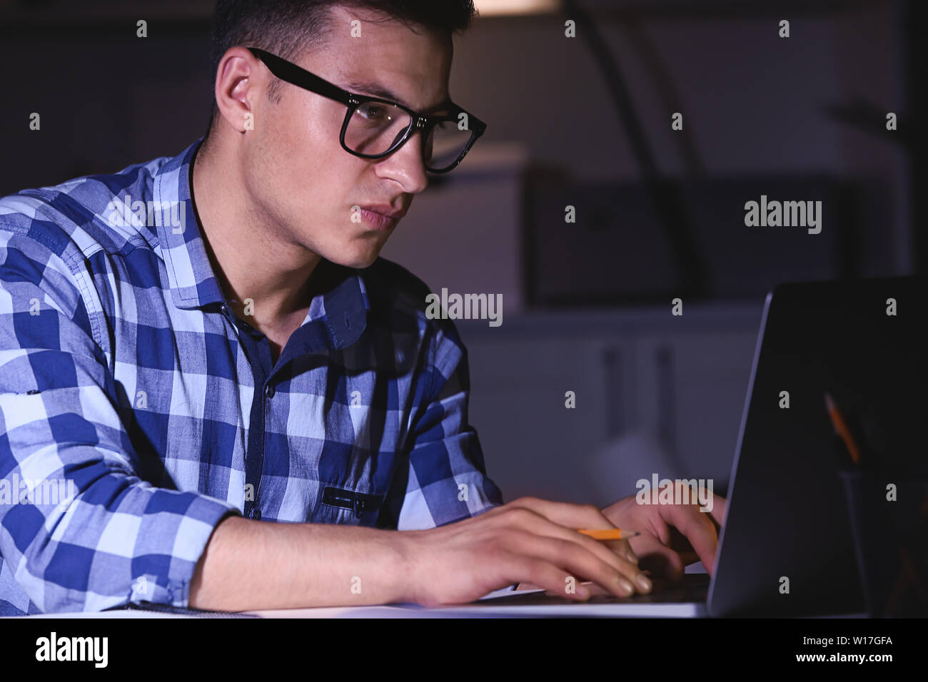 Busy young man working at home late in evening Stock Photo - Alamy