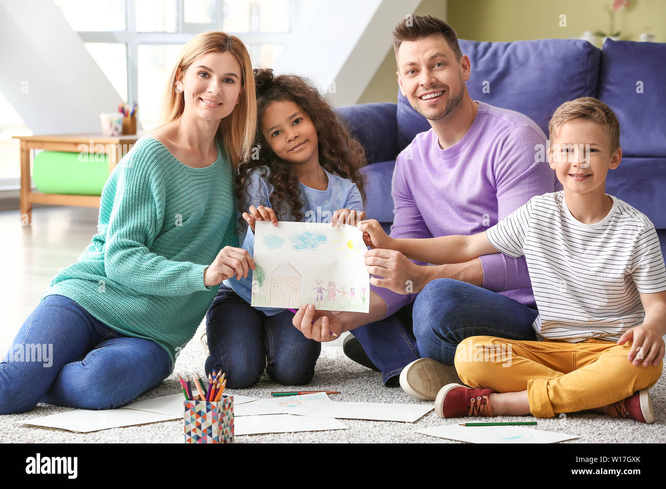 Happy couple and their little adopted children with drawing of home and ...