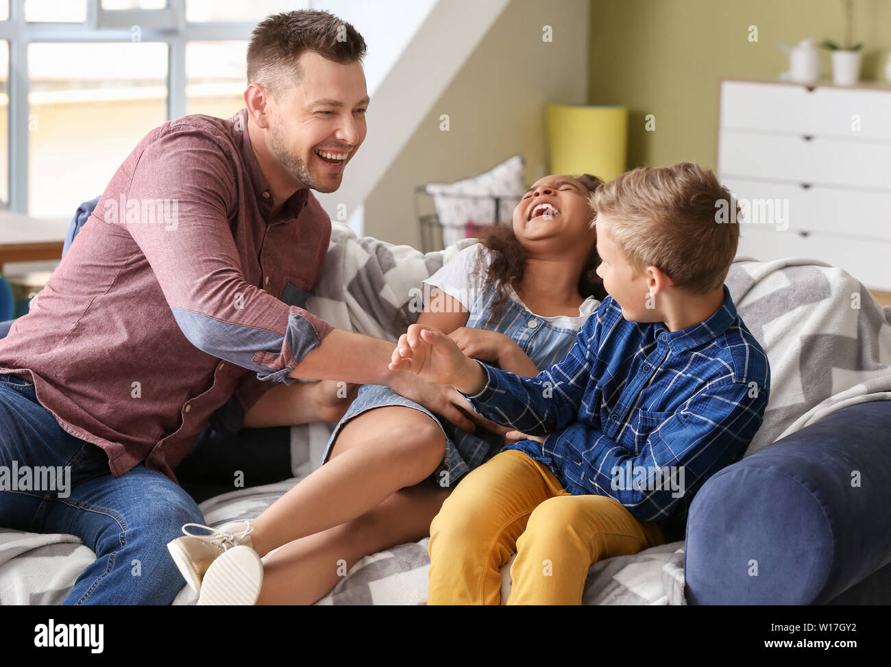Happy man playing with little adopted children at home Stock Photo - Alamy
