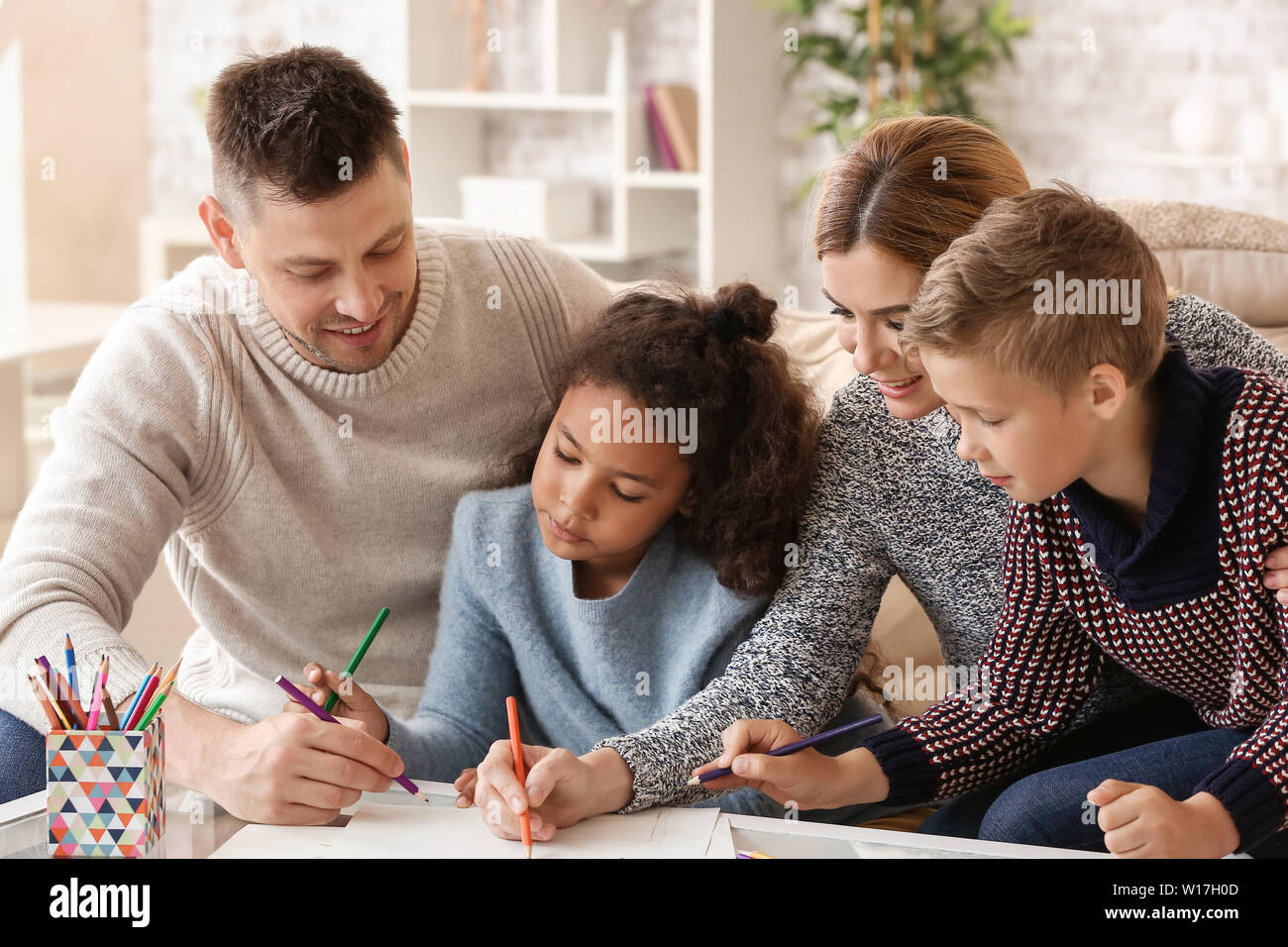 Happy couple with little adopted children drawing at home Stock Photo ...