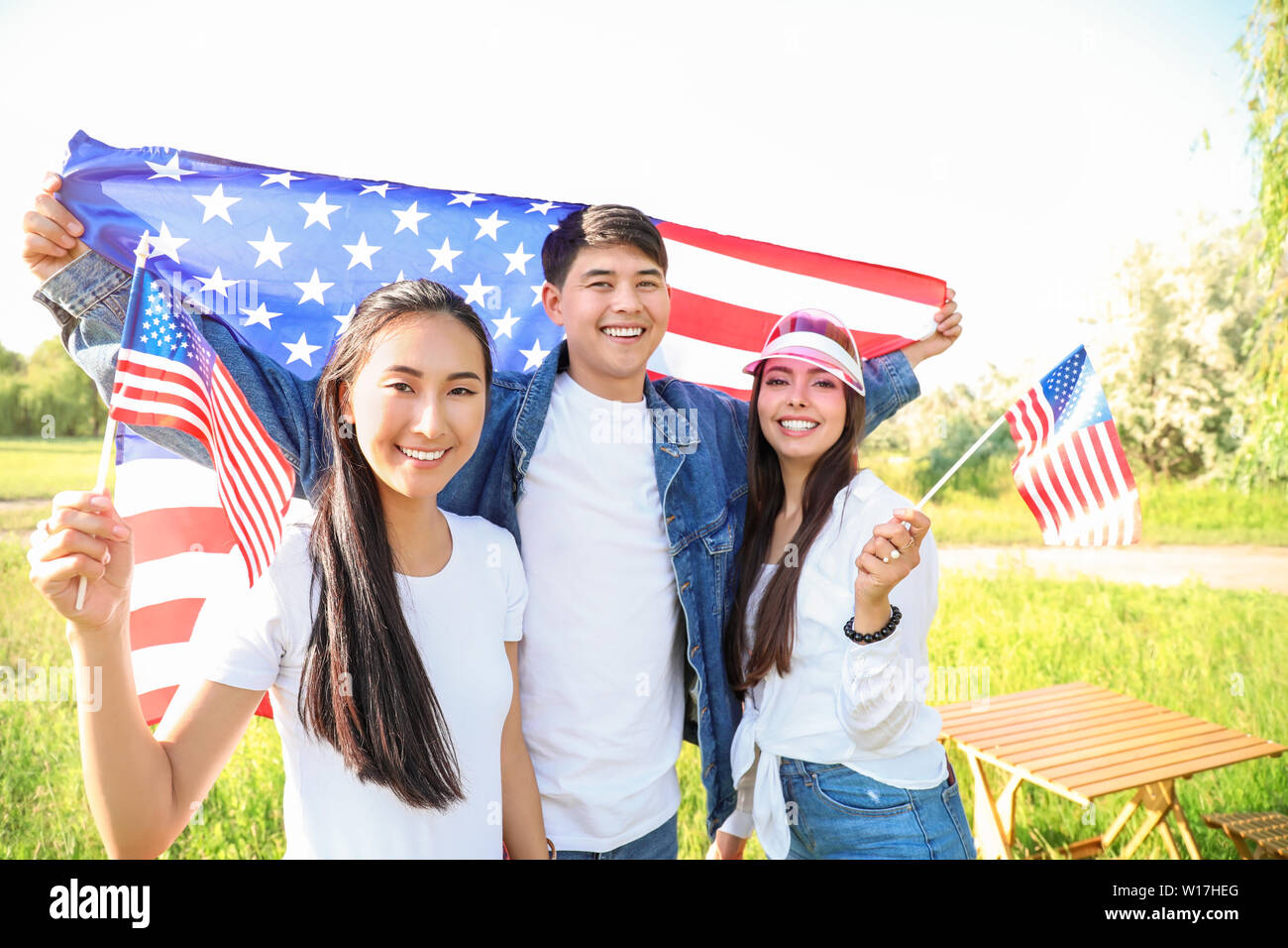 Young people with USA flags outdoors. Independence Day celebration ...