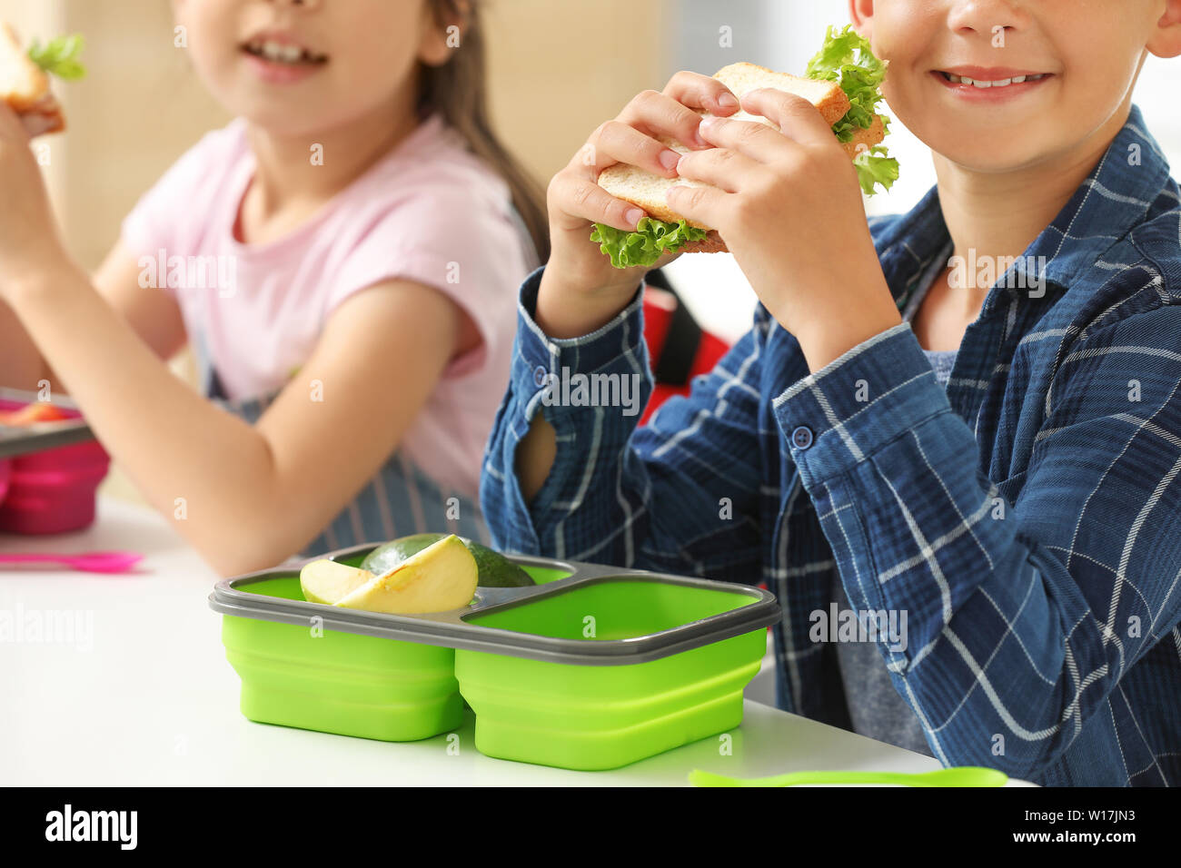 Schoolchildren having lunch in classroom Stock Photo - Alamy