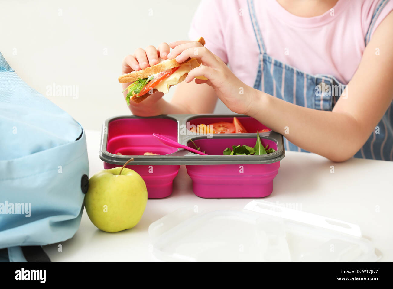 Little schoolgirl eating tasty lunch in classroom Stock Photo - Alamy